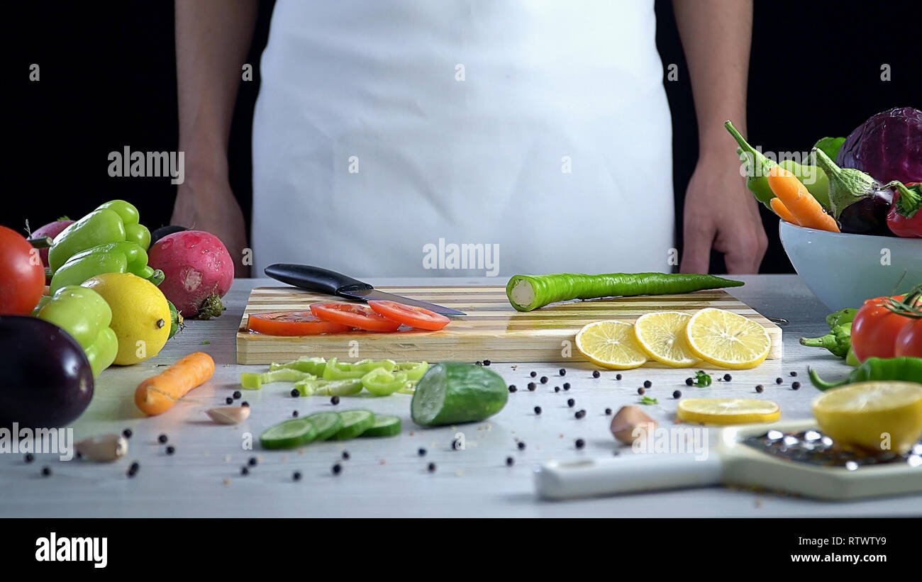 Man is cutting vegetables in the kitchen, slicing green bell pepper ...