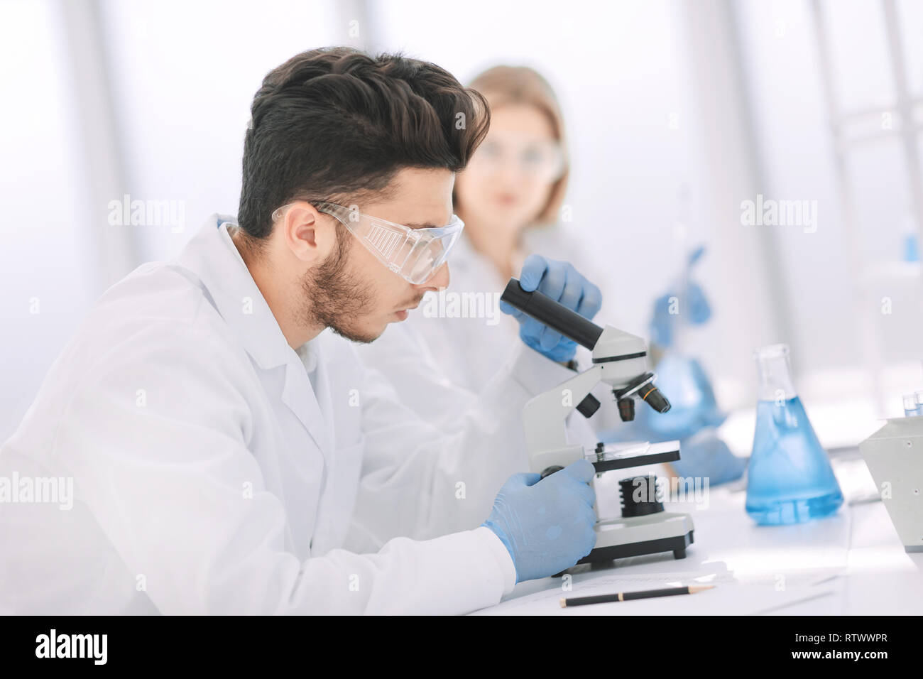 Close-up of a male scientific researcher looking at test tube while ...