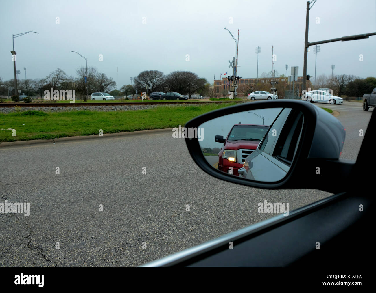 Side view mirror on an overcast day in Texas; reflection of red car in ...
