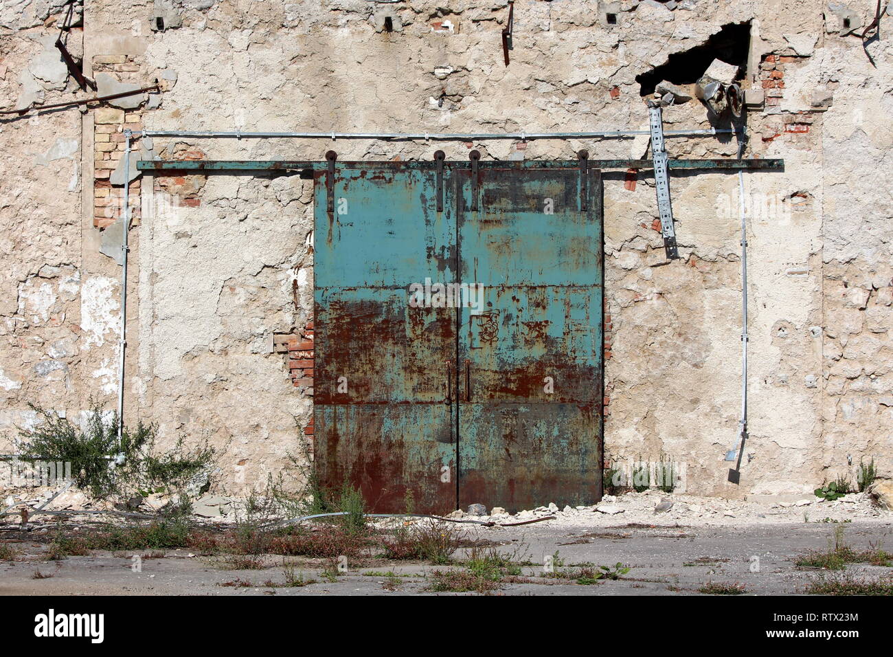 Almost completely rusted blue sliding metal doors mounted on abandoned ...