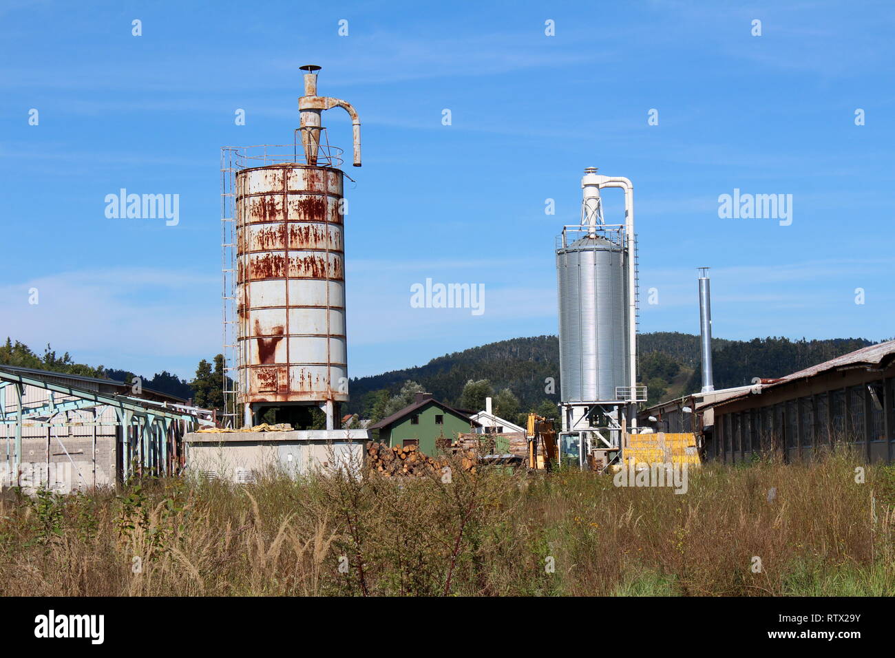 Brand new shiny metal and old rusted tall storage silos surrounded with ...