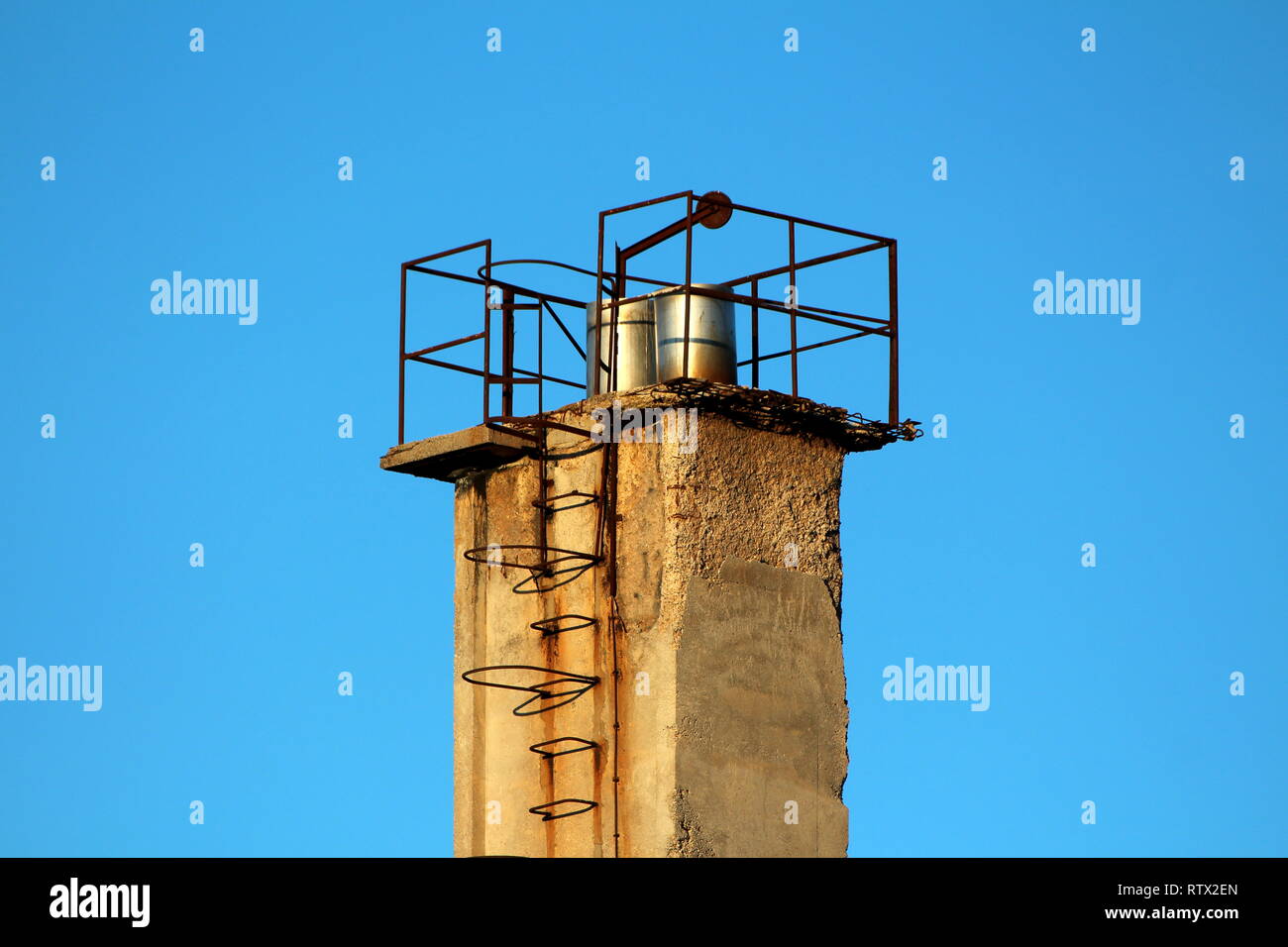 Concrete dilapidated cracked industrial chimney with mounted rusted ...