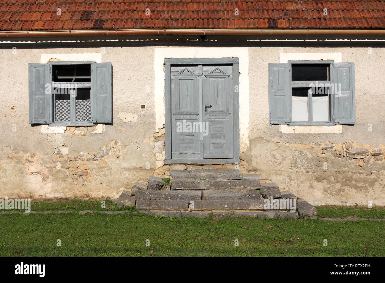 Front entrance to old abandoned house with freshly cut grass and stone ...