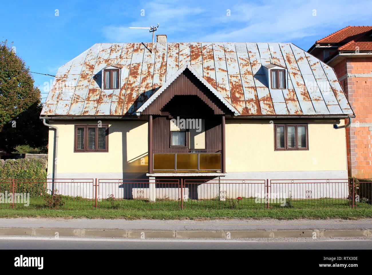 Ground level family house with partially rusted sheet metal roof and ...