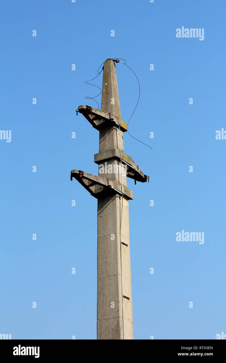 Massive concrete electrical utility pole with cut electrical wires ...
