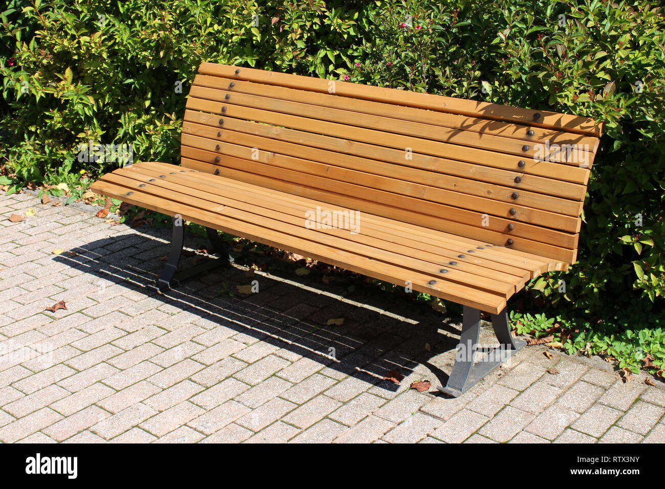 New public bench made of dense narrow wooden boards mounted on stone ...