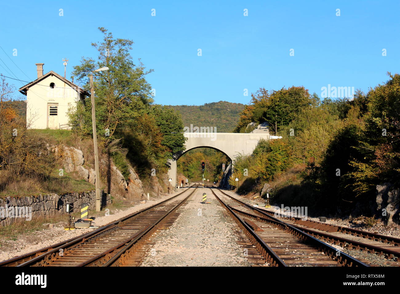 Railway tracks going under concrete bridge surrounded with gravel and ...