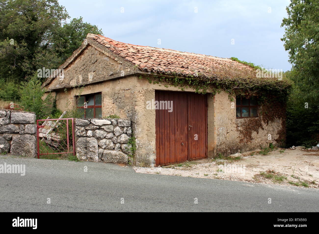 Rarely used old garage with rusted metal doors and small windows ...