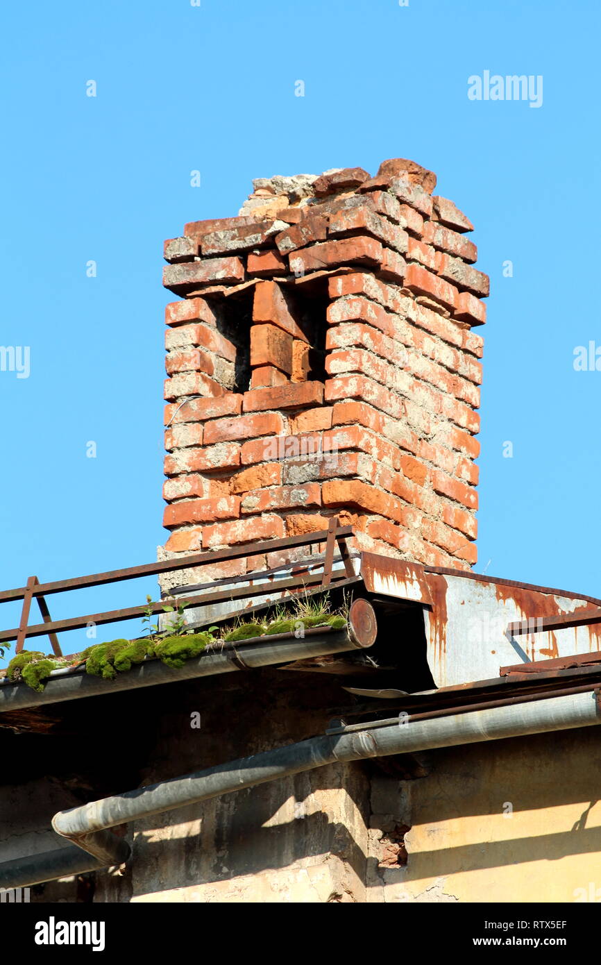 Ruins of old red brick chimney on top of abandoned building with metal ...
