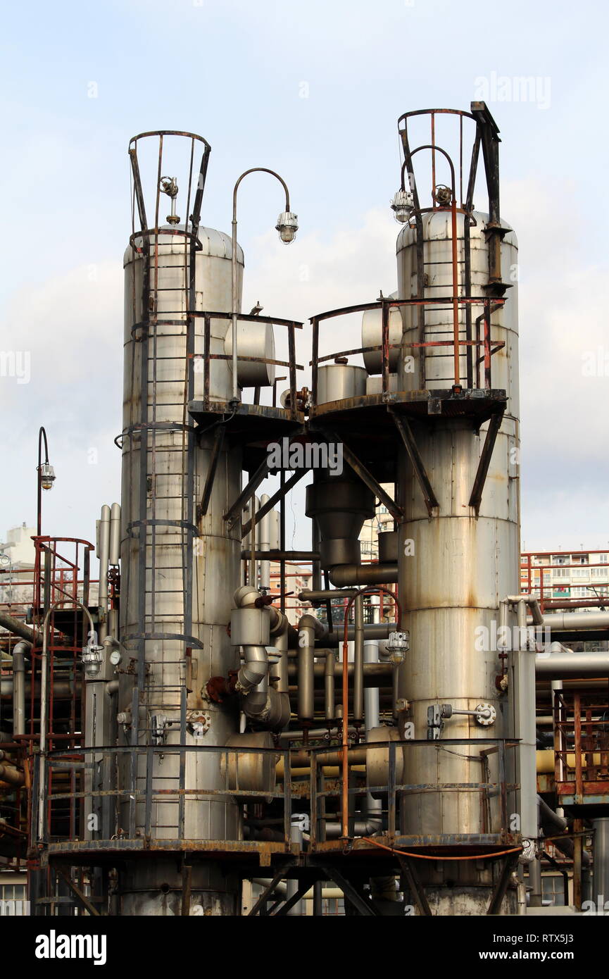 Rusted metal storage silos connected with complex pipeline network at ...