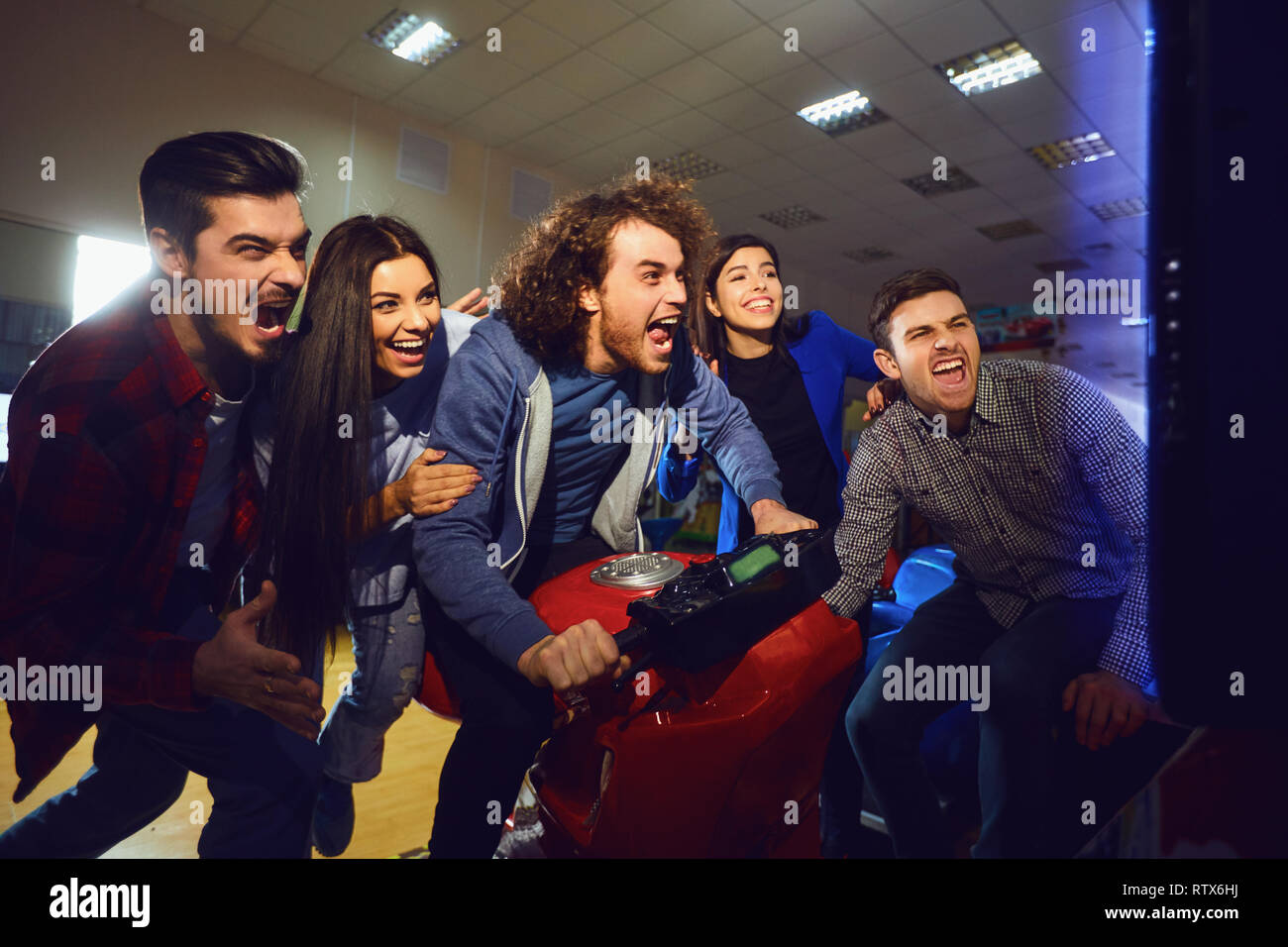A group of friends playing arcade machine Stock Photo - Alamy
