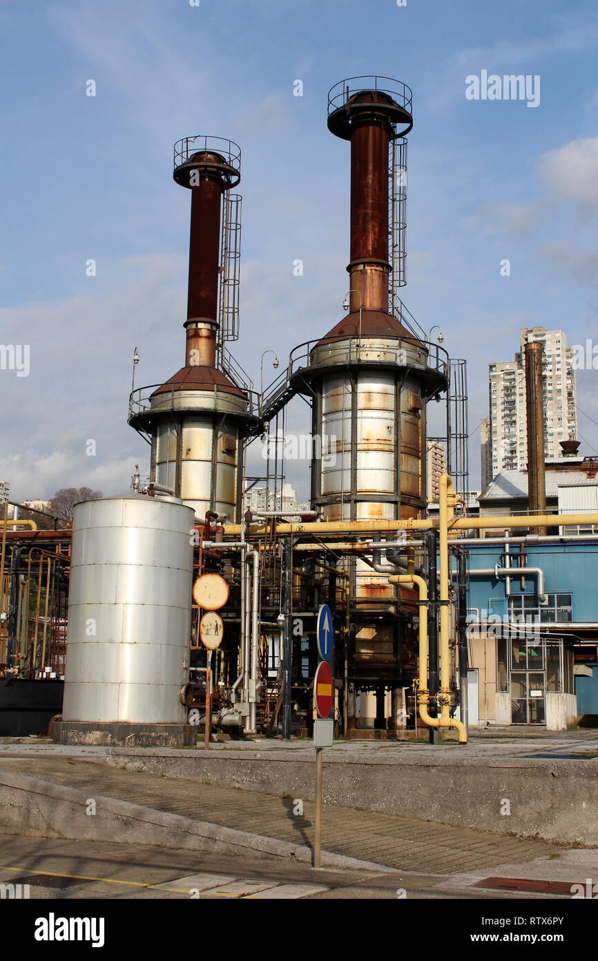 Two large rusted industrial silos surrounded with multiple pipelines at ...