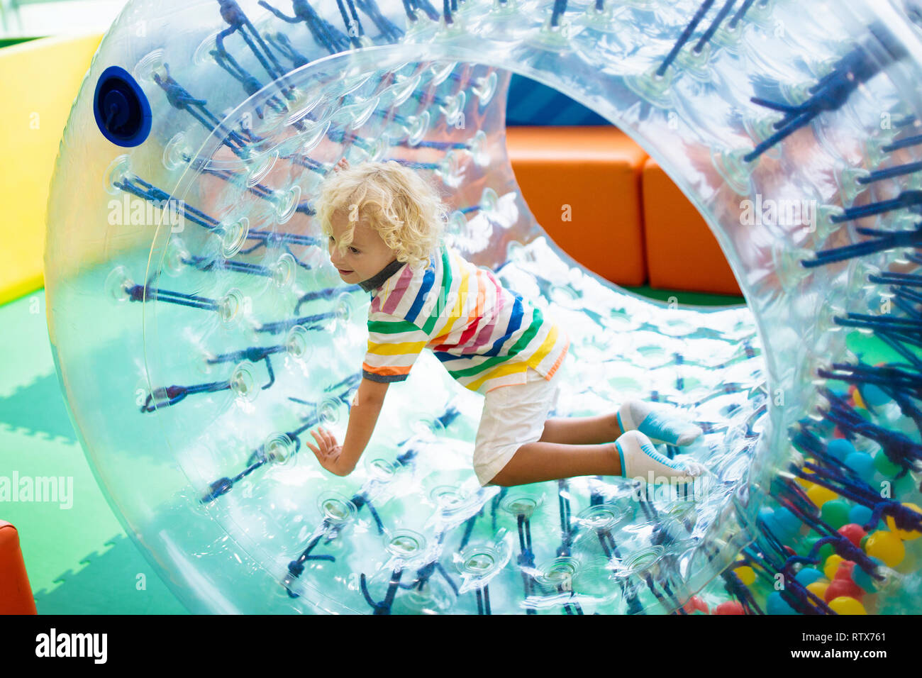 Child in roller wheel jumping on colorful playground trampoline. Kids ...