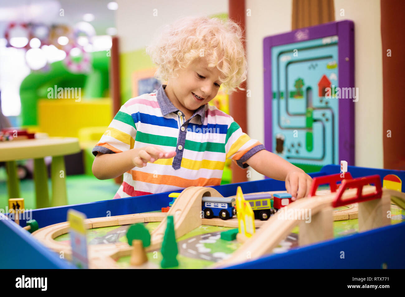 Kids play toy railroad. Little blond curly boy with wooden trains in ...