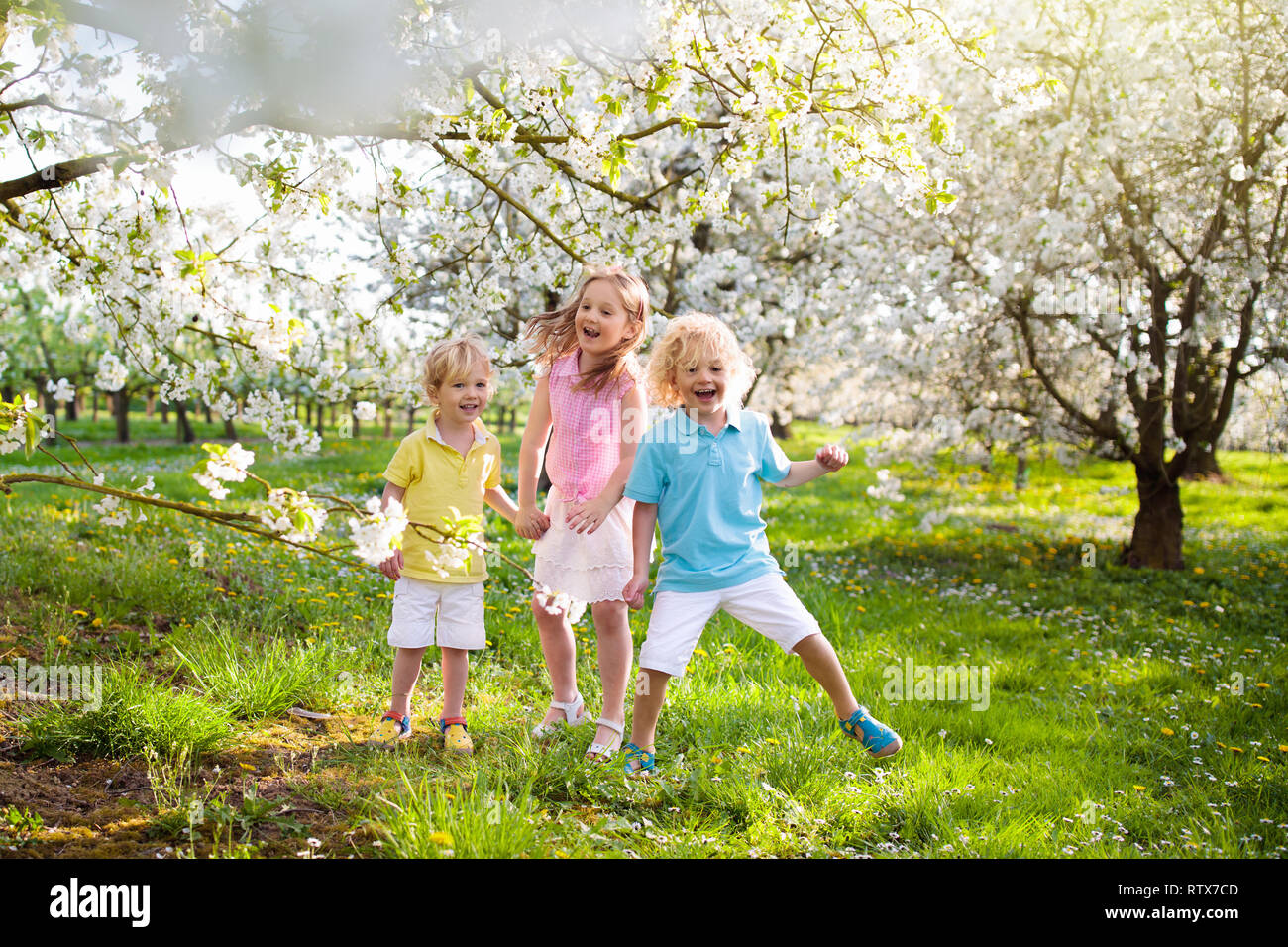 Kids playing in spring park. Children running in sunny garden with ...