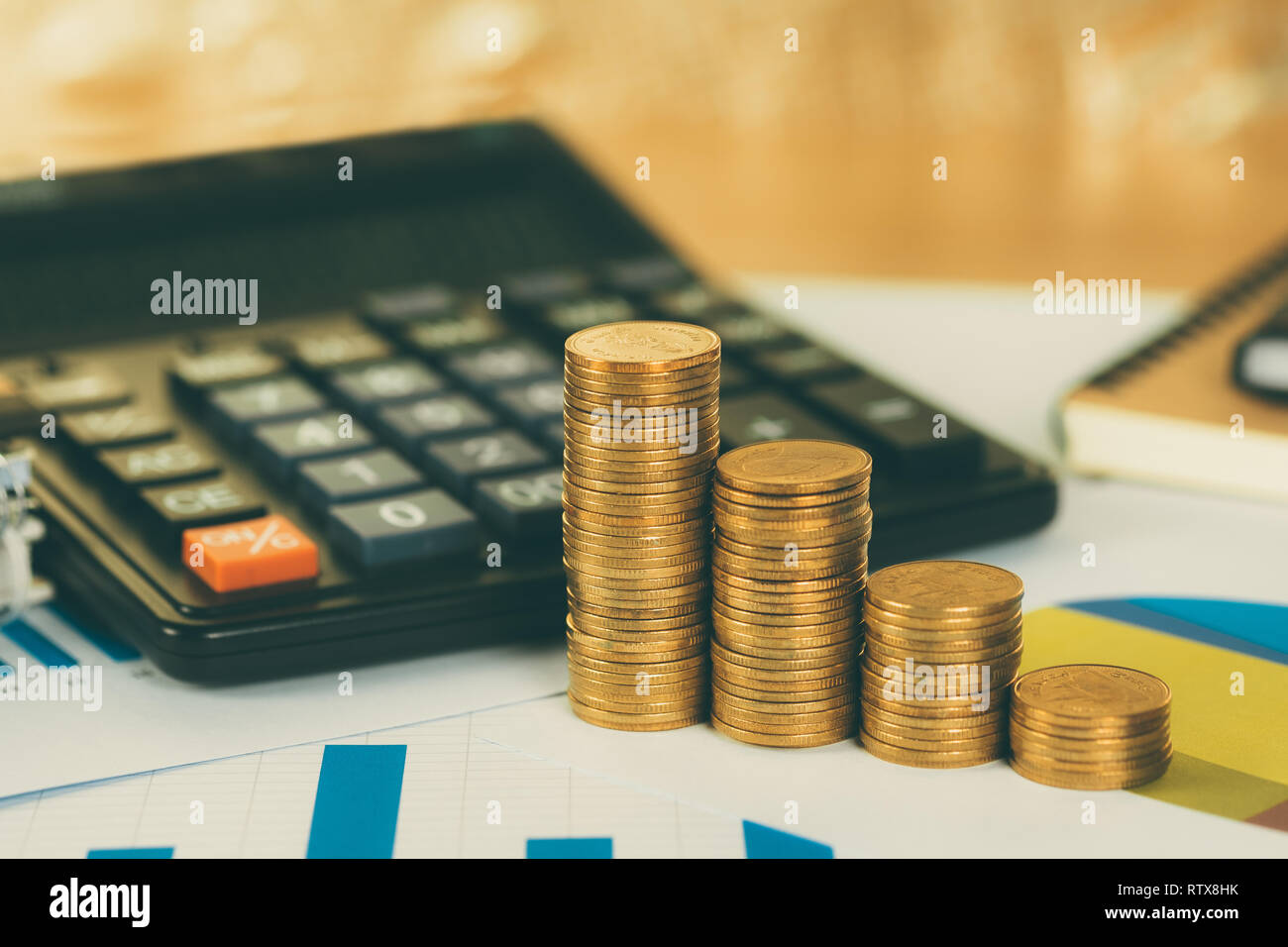 Coin stack and financial graph paper sheet with calculator on working ...