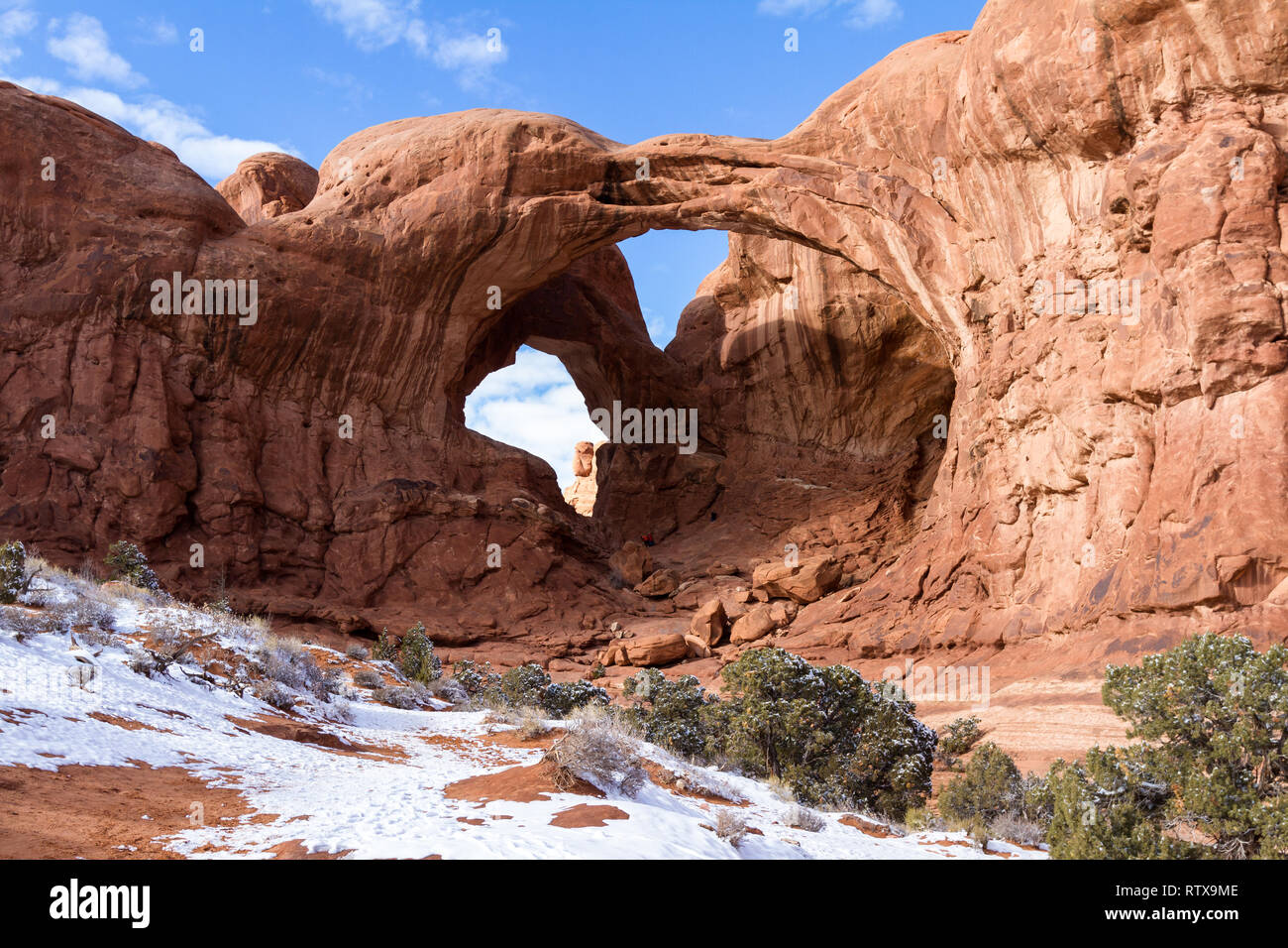 Double arch with a bit of snow in the ground and people under the arch ...