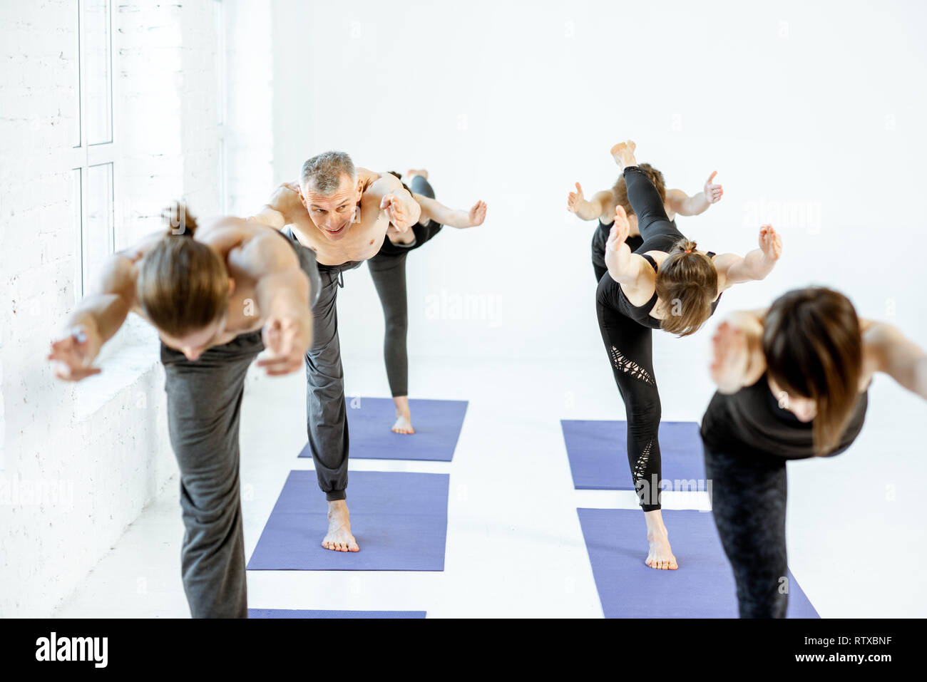 Young group of people practising yoga, keeping pose arranged together ...