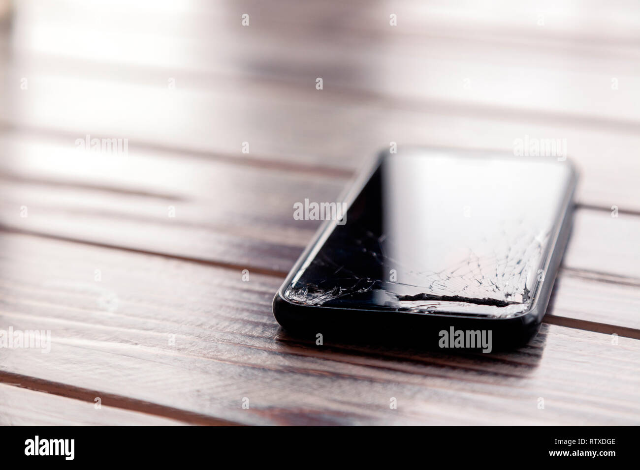 Сloseup black smartphone with a broken screen glass lying on wooden ...
