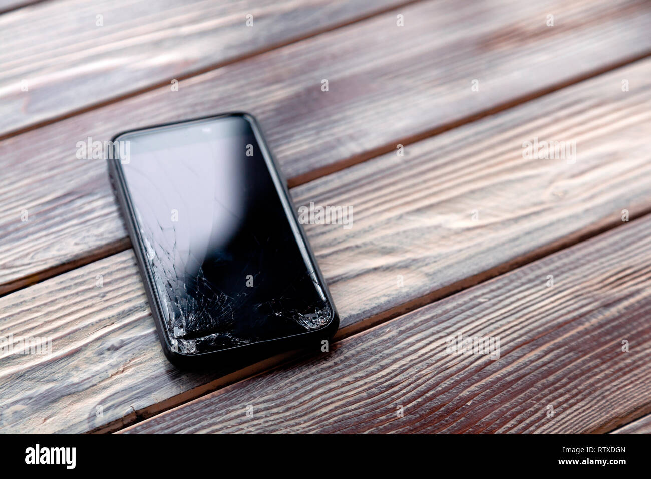 Сloseup black smartphone with a broken screen glass lying on wooden ...