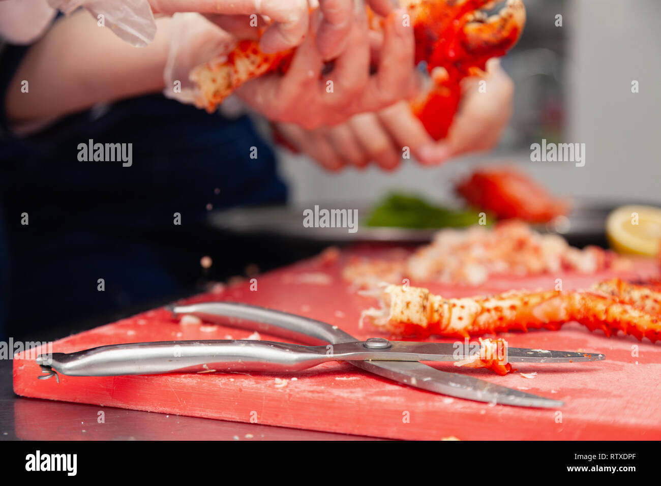 Cook in uniform is carving fresh red big boiled prepared blue kamchatka ...