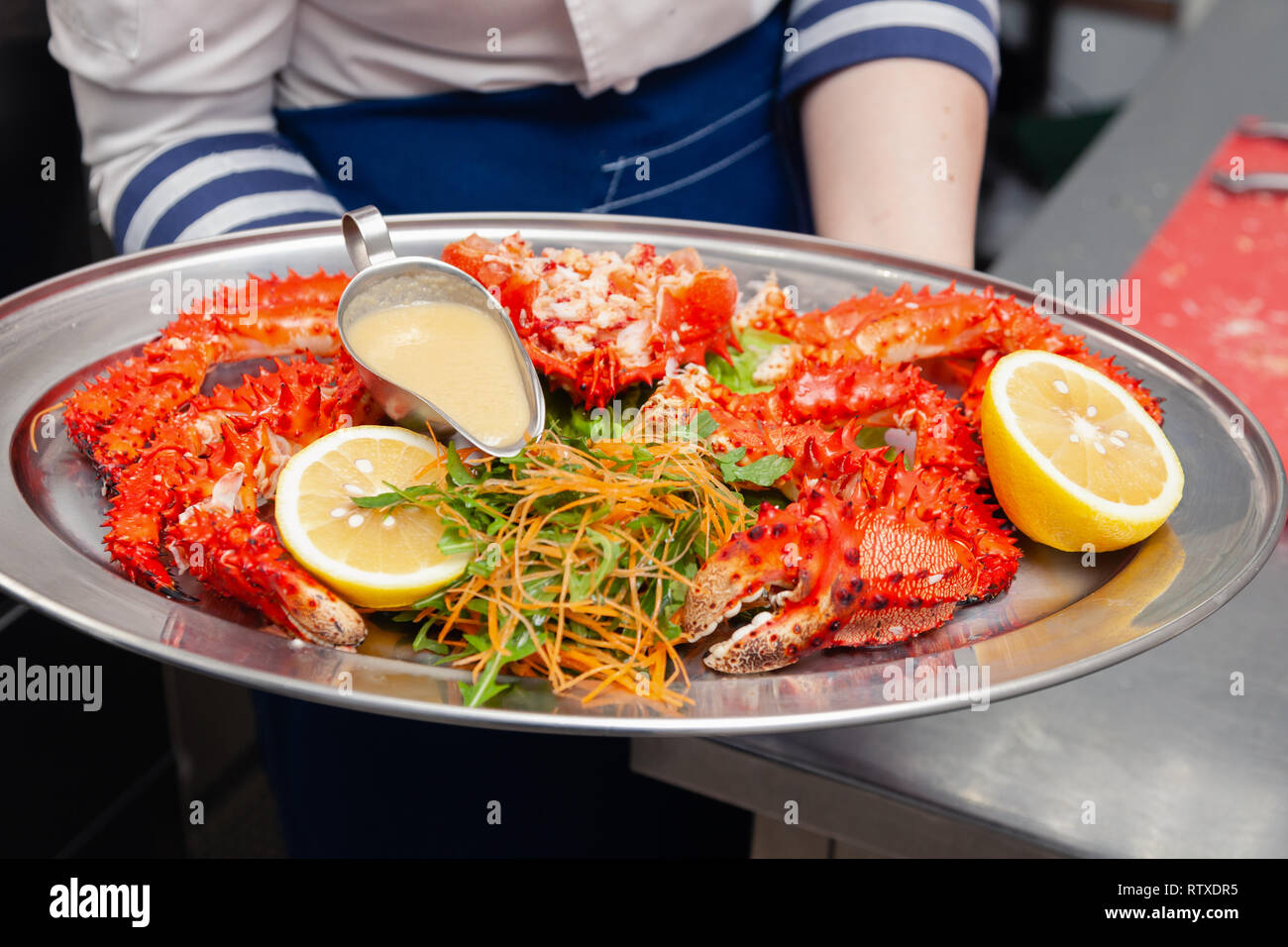 Chef cook in uniform hold metal dish with fresh red big boiled prepared ...