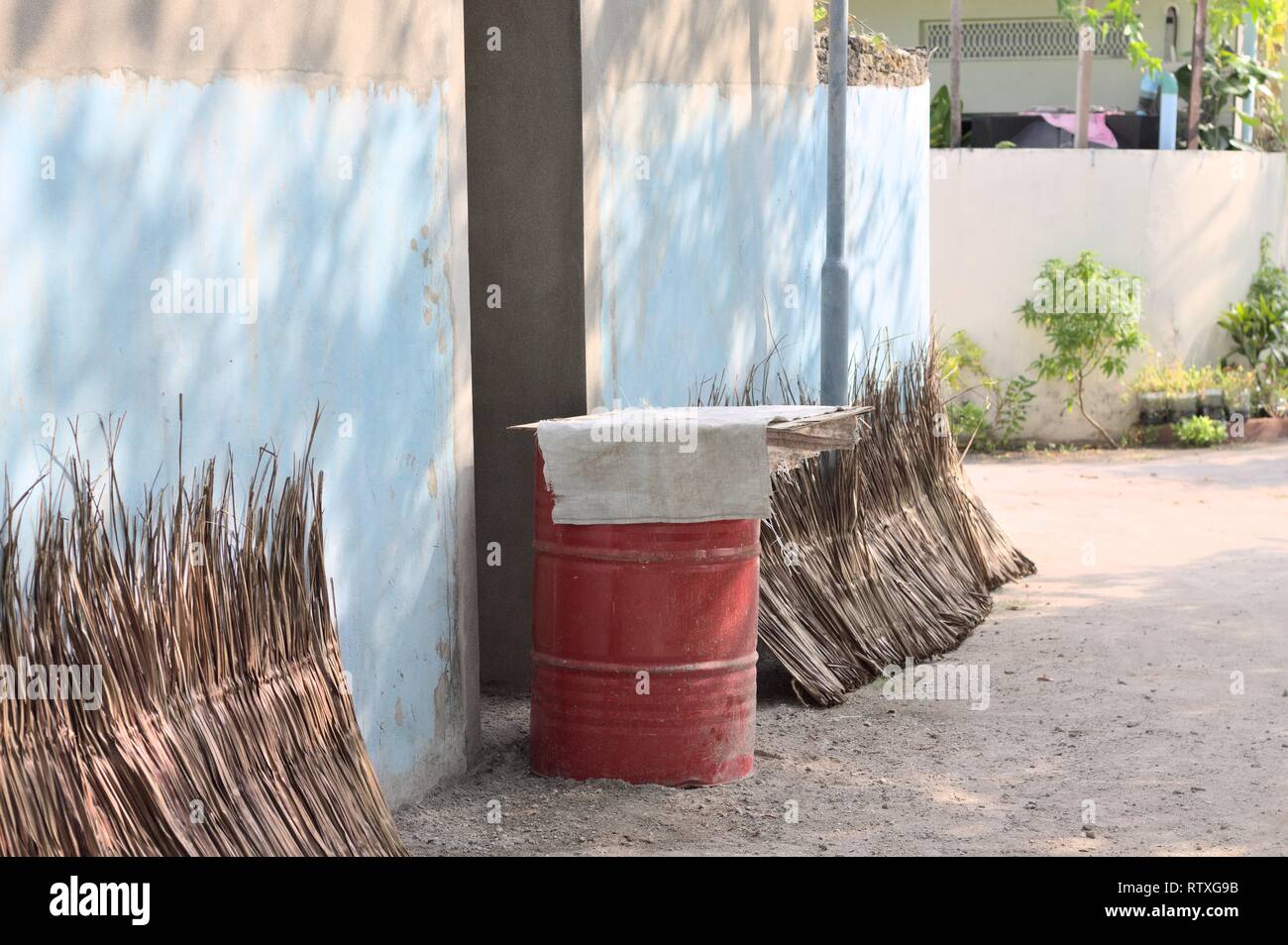 Red oil tank in front of the door and stacked dried palm leaves (Ari ...