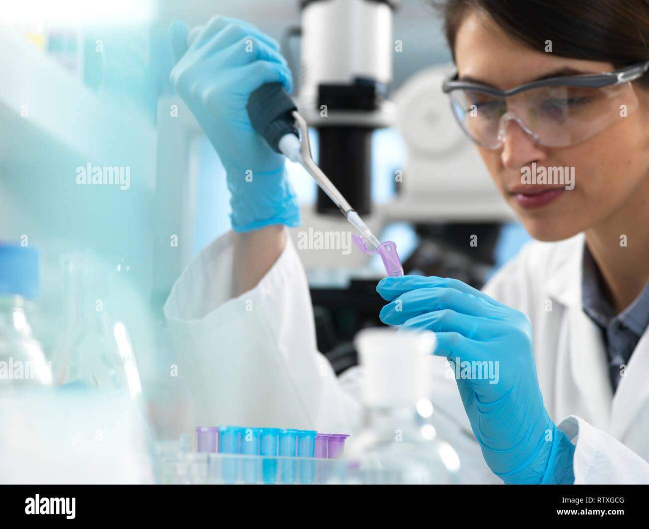 Female scientist pipetting dna or chemical sample into eppendorf vial ...