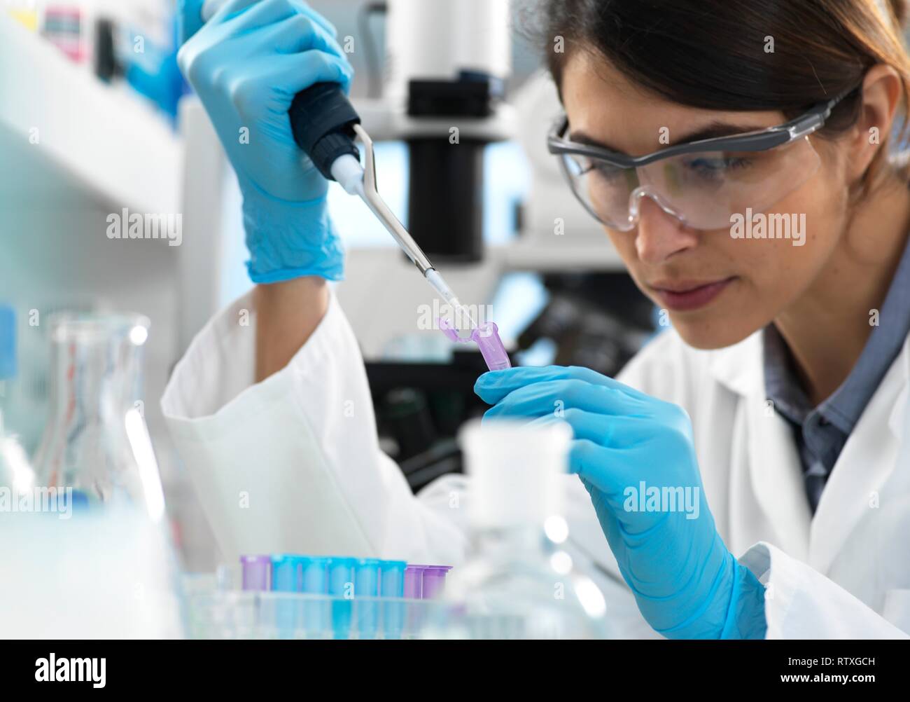 Scientist pipetting sample into a tube for analytical testing in the ...
