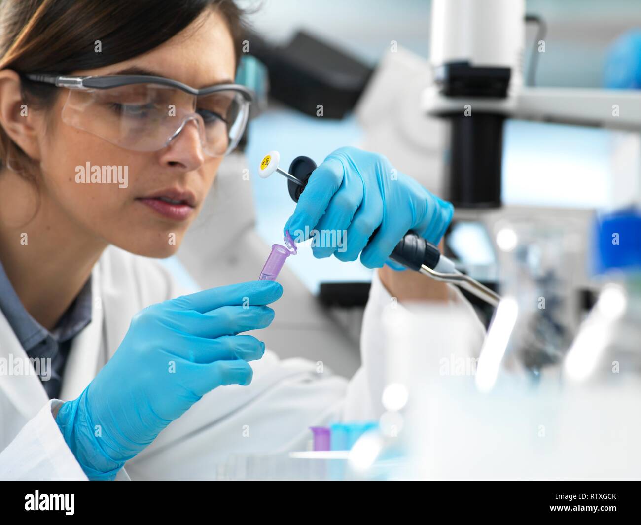 Scientist pipetting sample into a tube for analytical testing in the ...