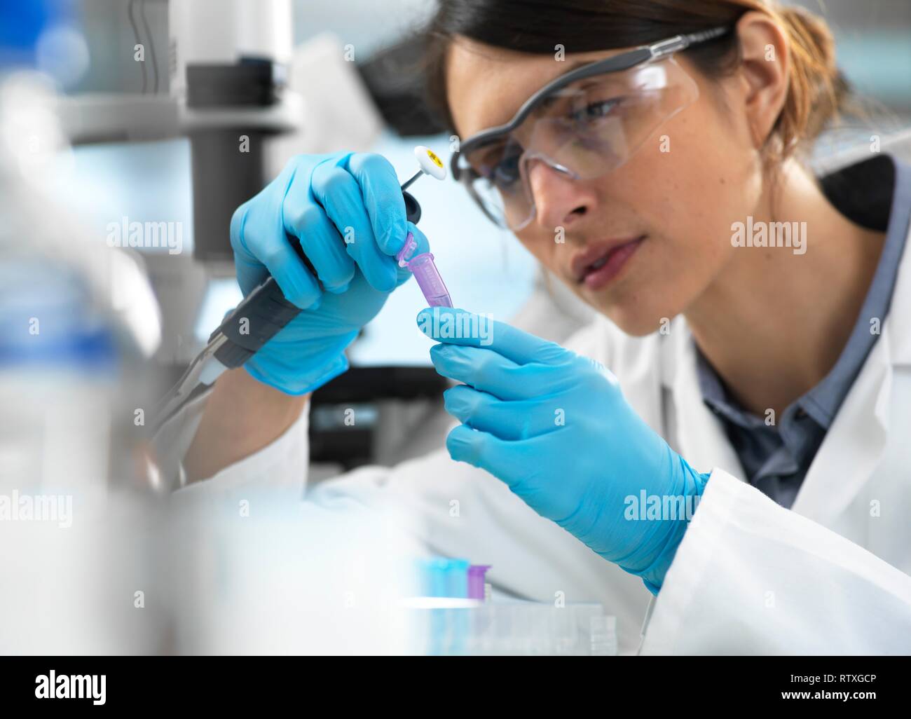Scientist pipetting sample into a tube for analytical testing in the ...