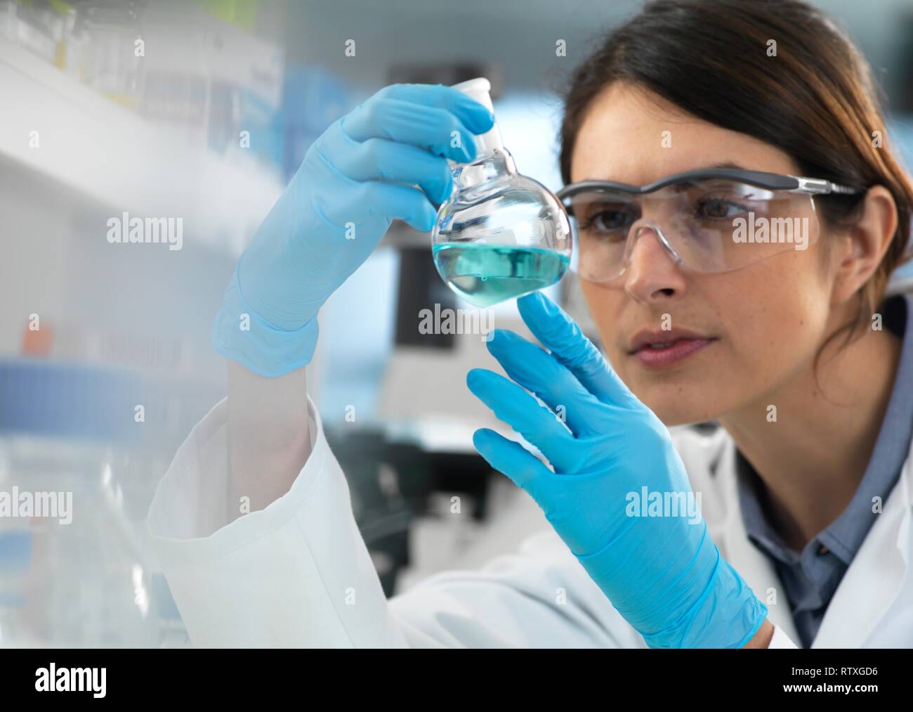 Scientist examining a solution in a laboratory flask during an experiment Stock Photo - Alamy