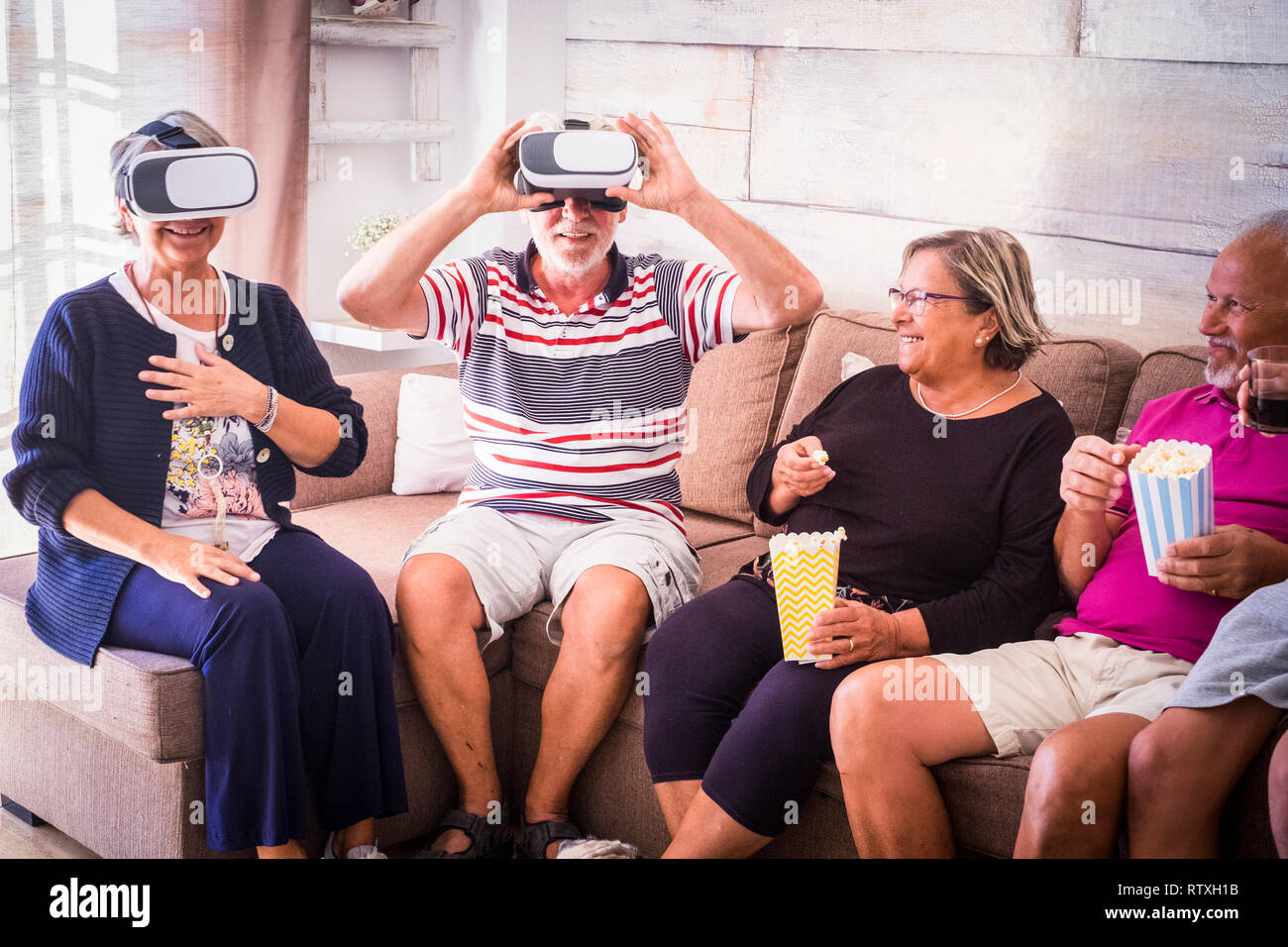 Group of aged old friends have fun at home with vr goggled headset and ...