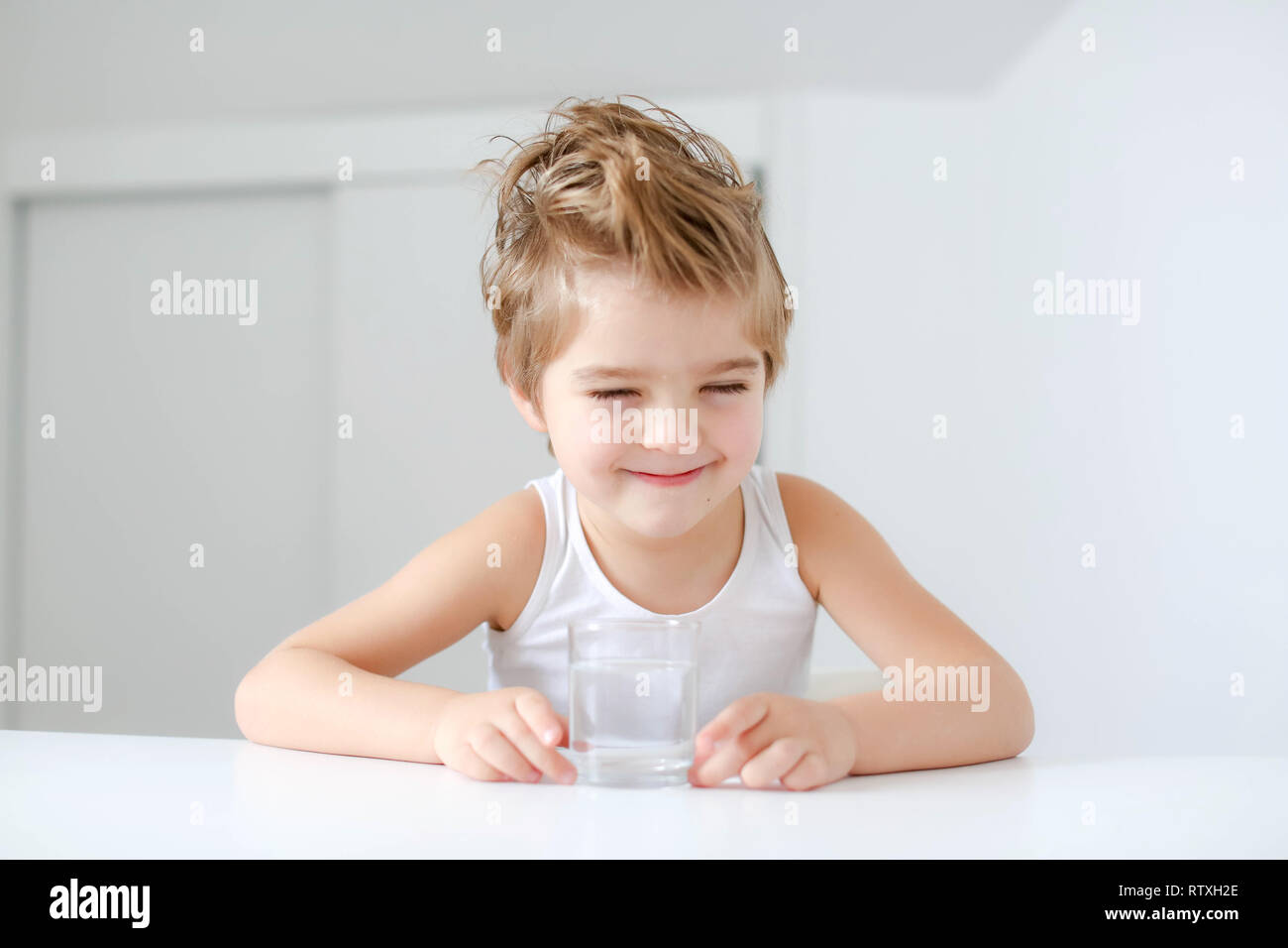 Cute smiling boy with glass of water isolated on a white background ...