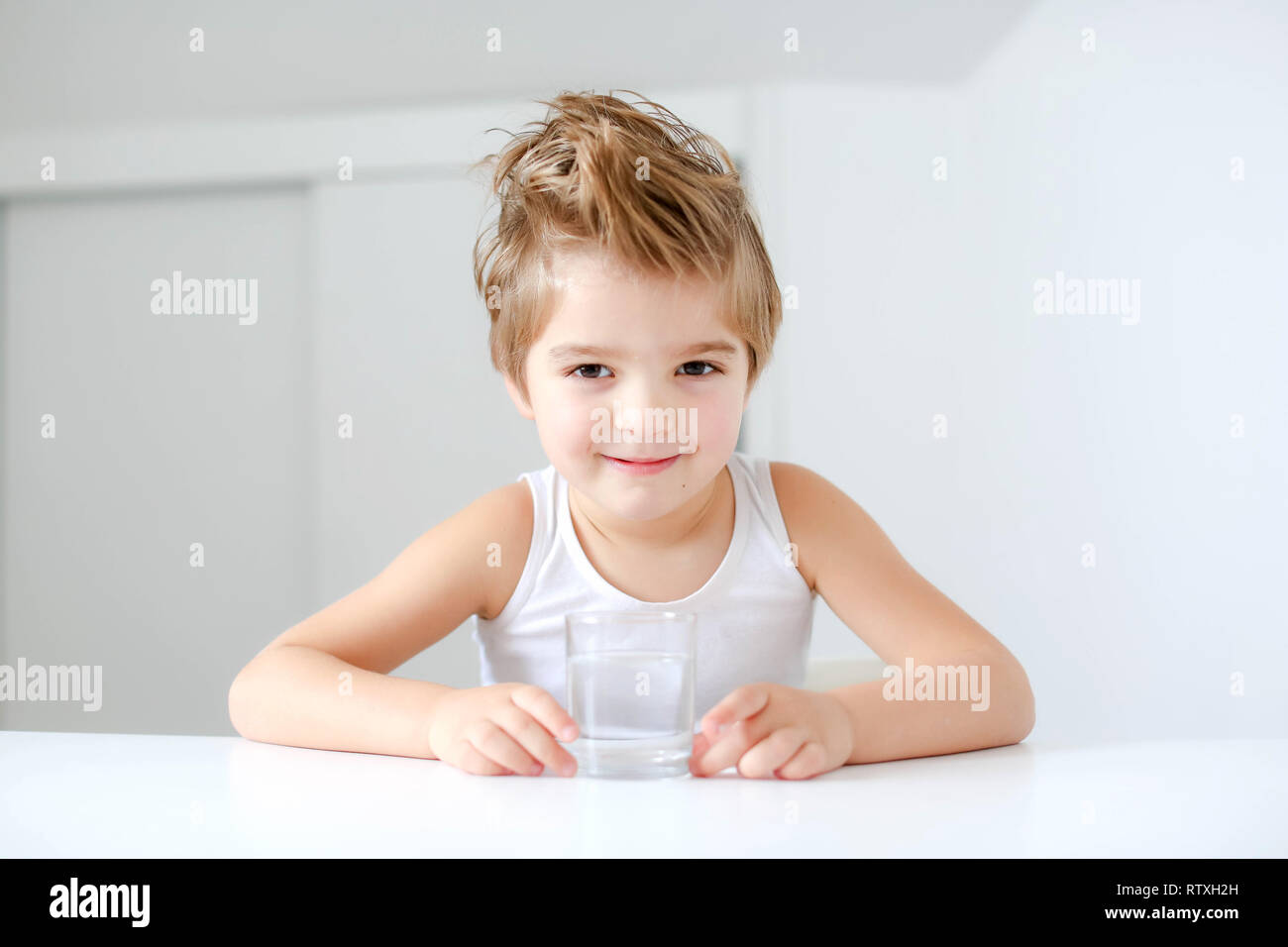 Cute smiling boy with glass of water isolated on a white background ...