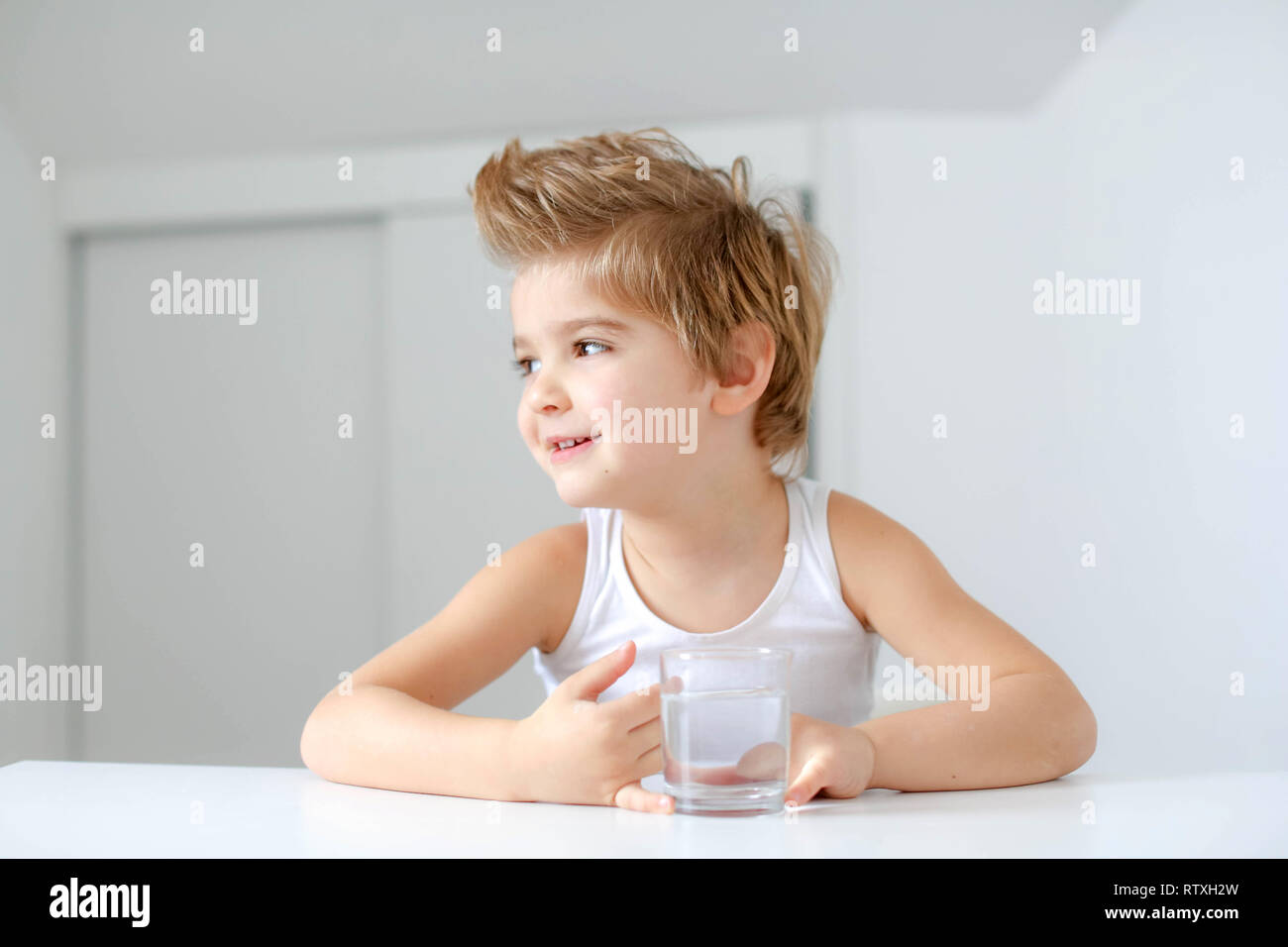 Cute smiling boy with glass of water isolated on a white background ...