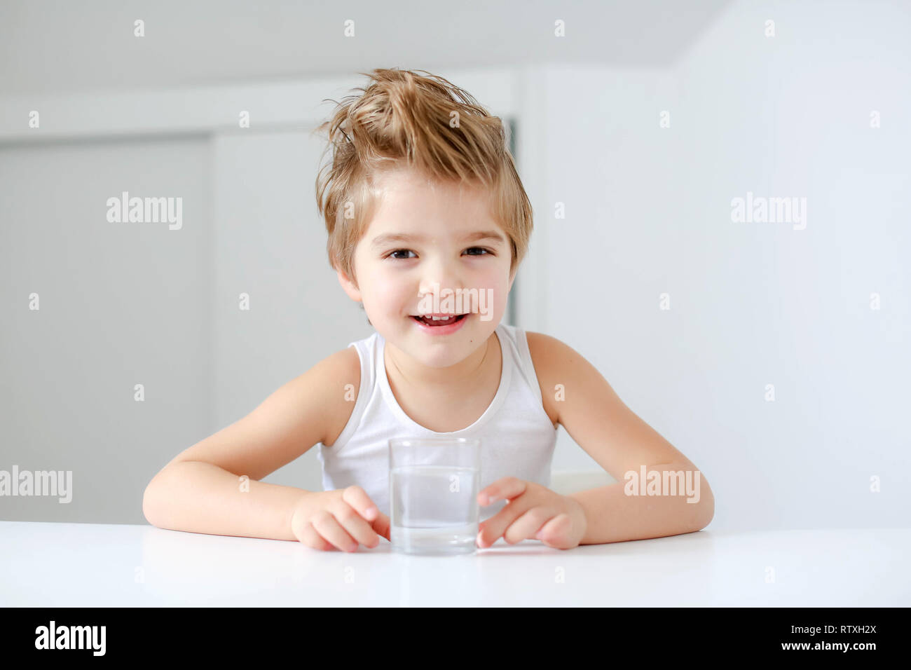 Cute smiling boy with glass of water isolated on a white background ...