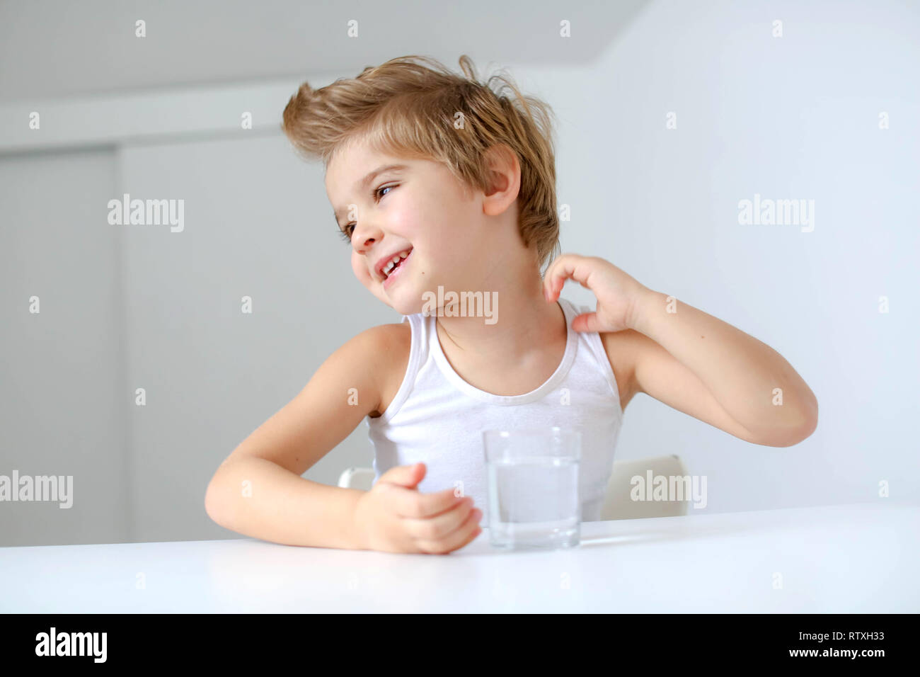 Cute smiling boy with glass of water isolated on a white background ...