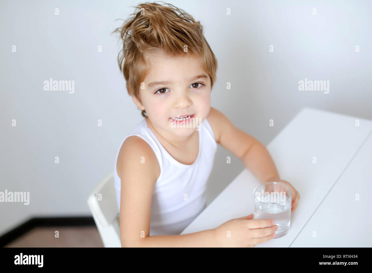 Cute smiling boy with glass of water isolated on a white background ...