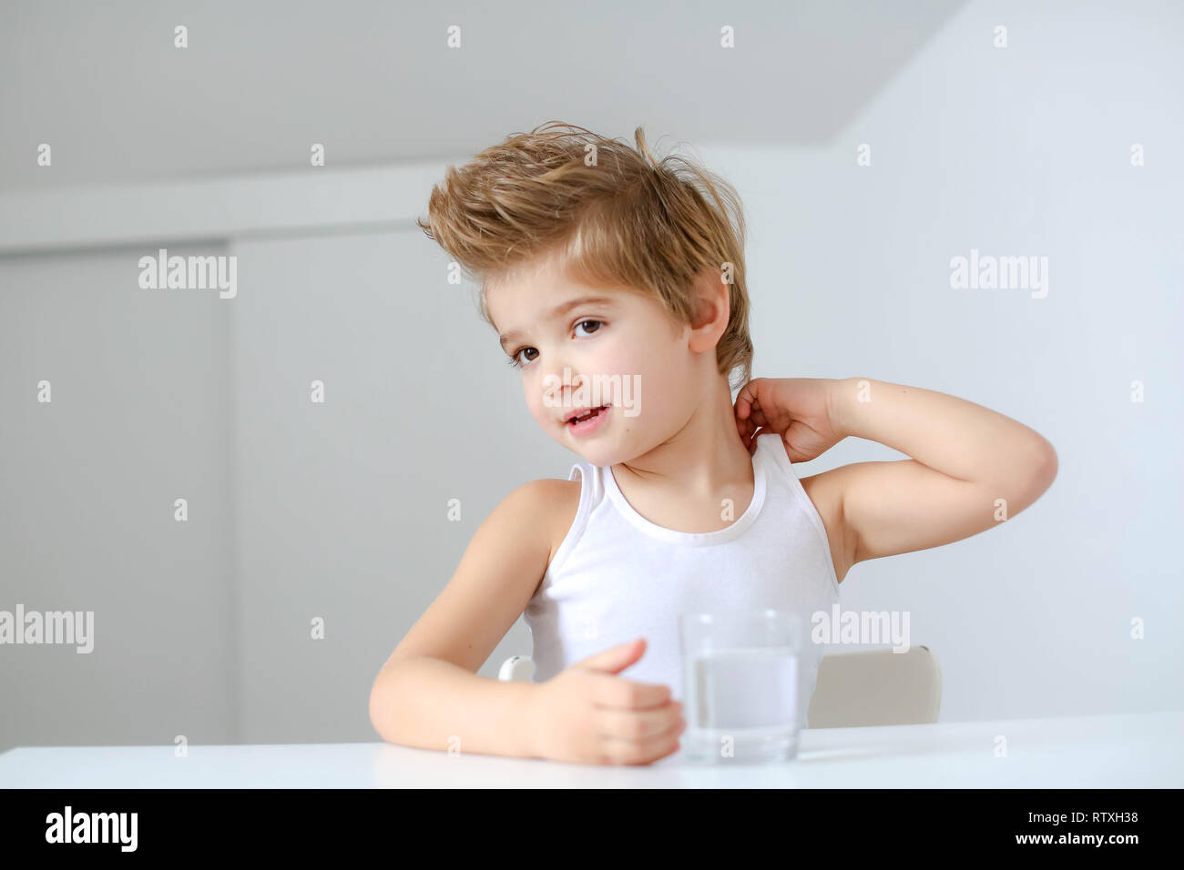 Cute smiling boy with glass of water isolated on a white background ...