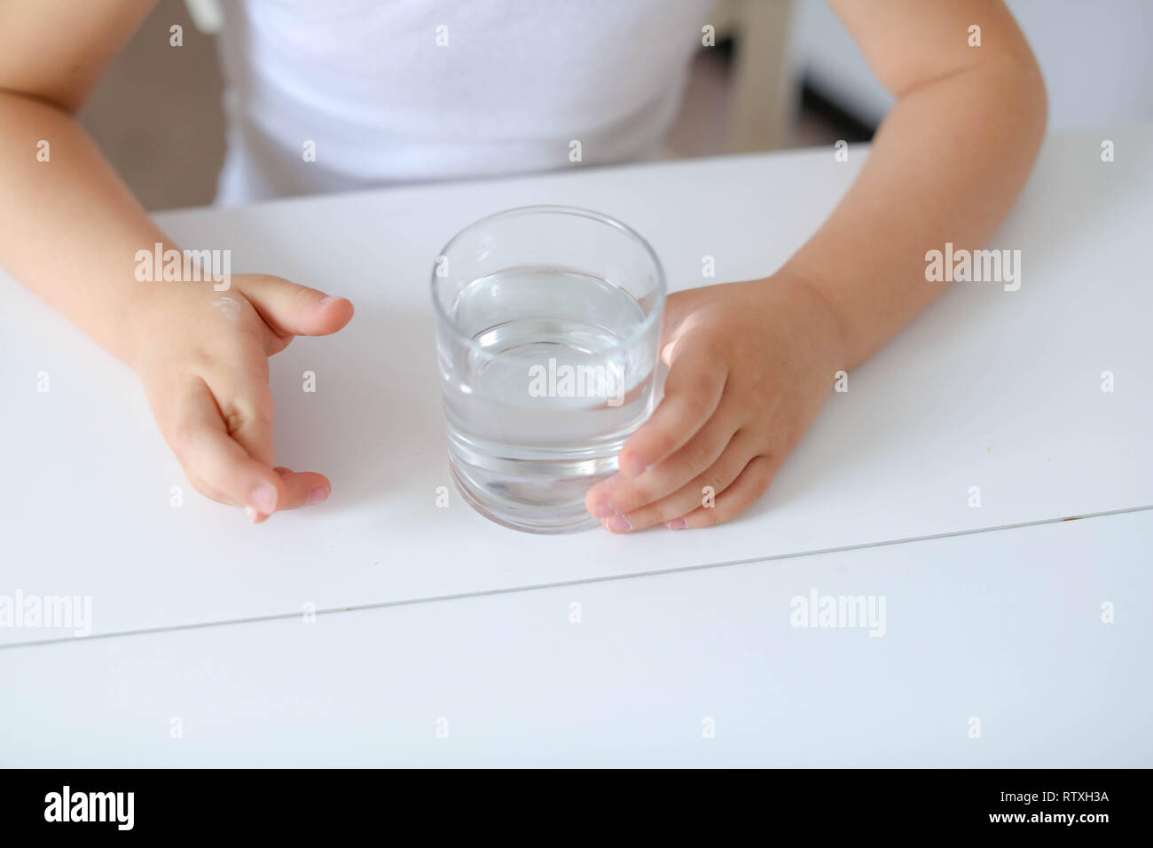 Cute smiling boy with glass of water isolated on a white background ...