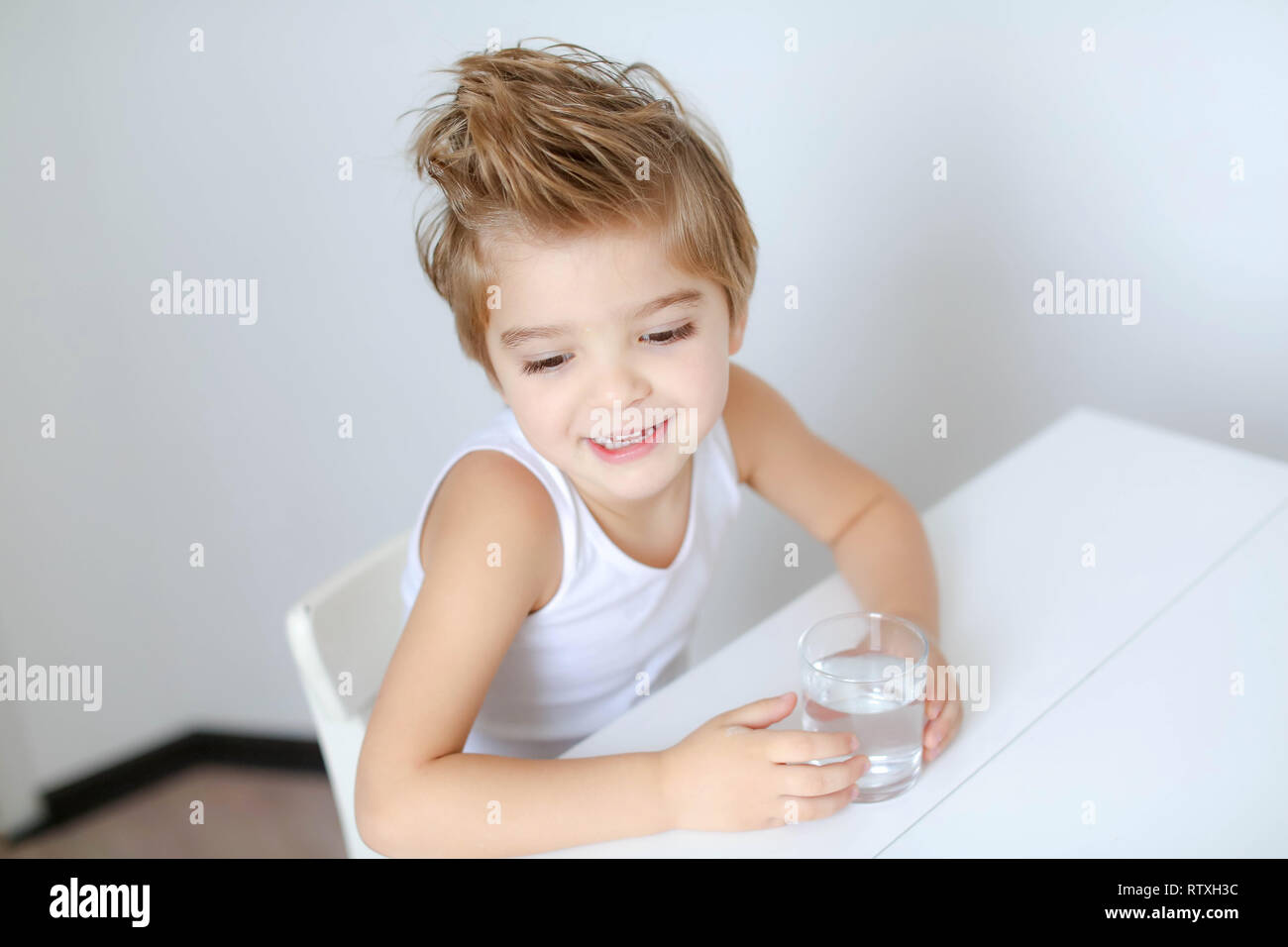 Cute smiling boy with glass of water isolated on a white background ...