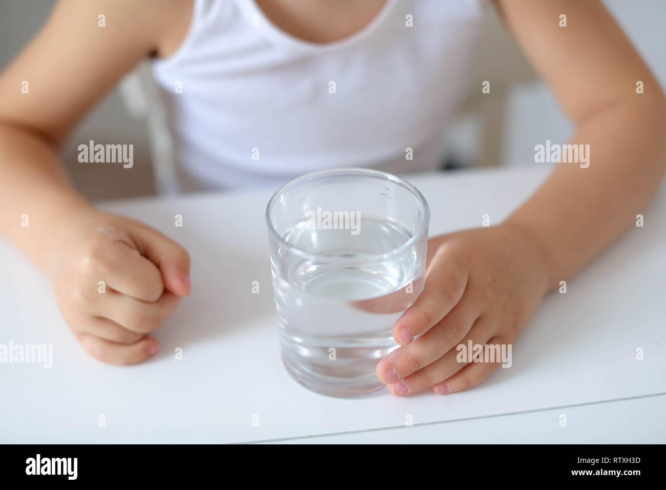 Cute smiling boy with glass of water isolated on a white background ...