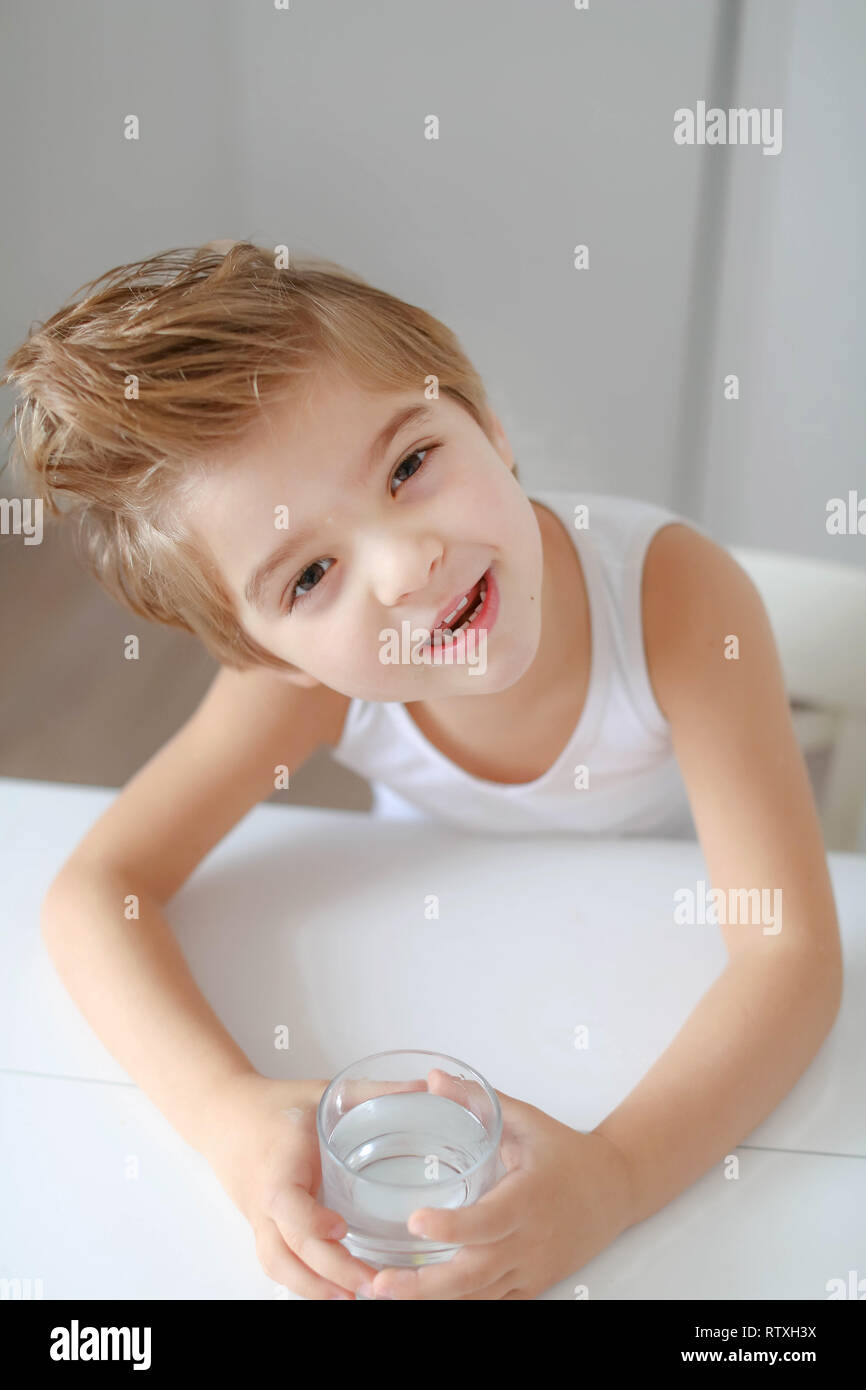 Cute smiling boy with glass of water isolated on a white background ...