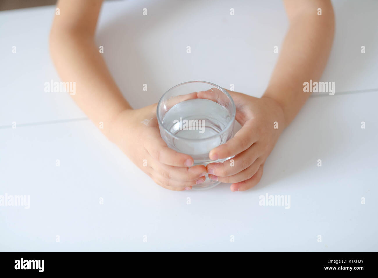 Cute smiling boy with glass of water isolated on a white background ...