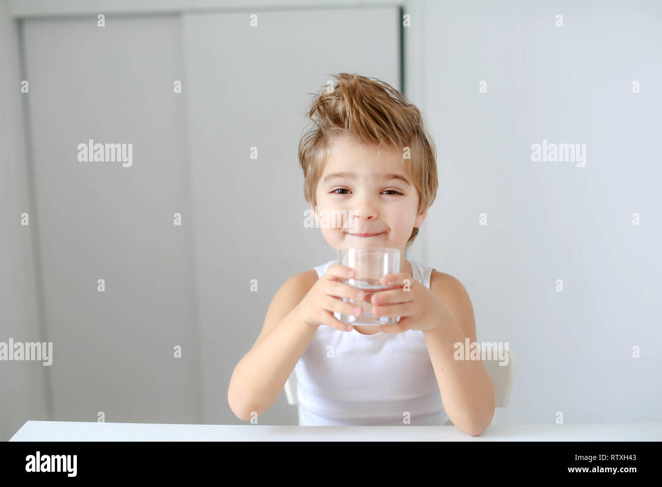 Cute smiling boy with glass of water isolated on a white background ...