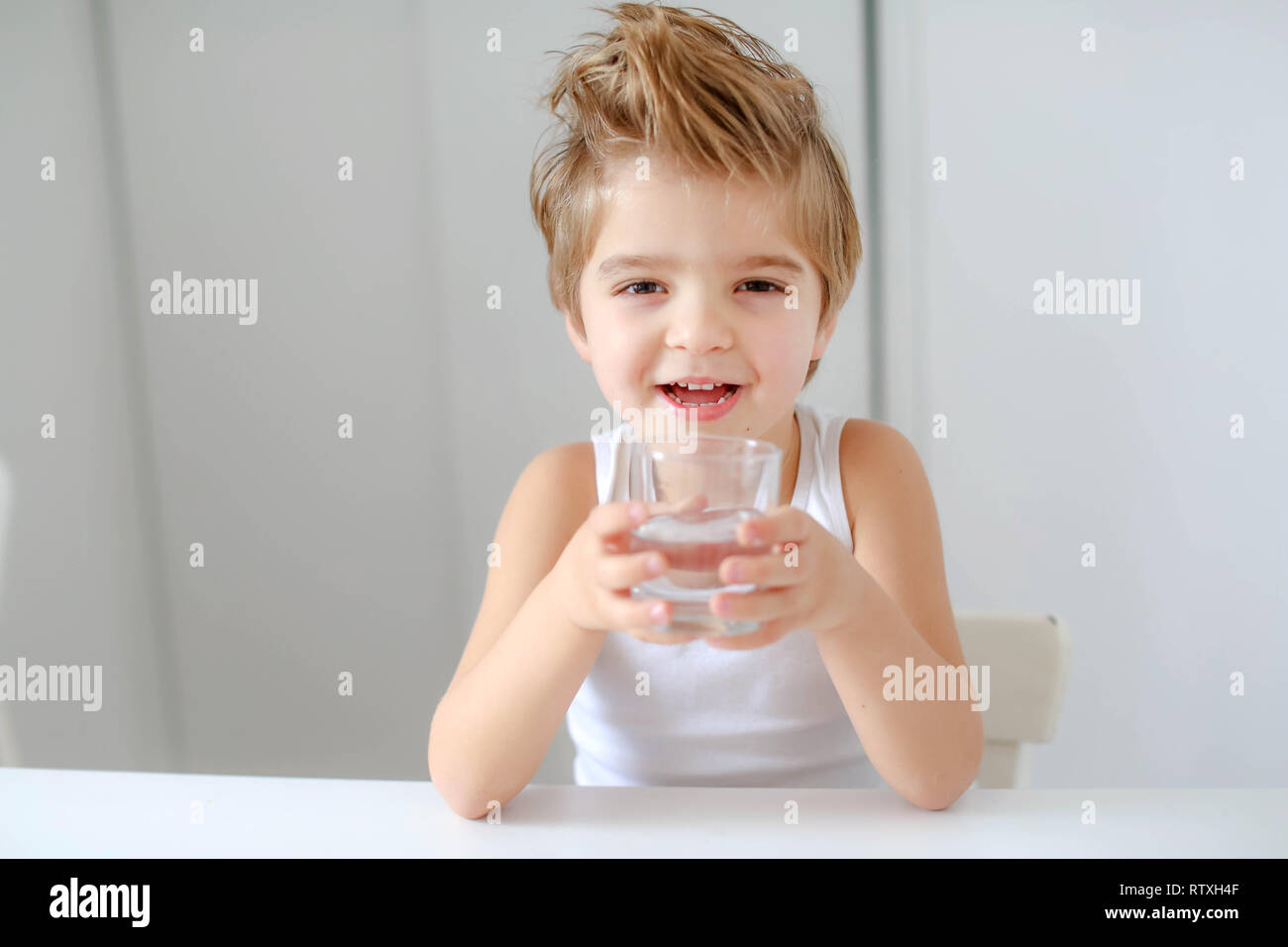 Cute smiling boy with glass of water isolated on a white background ...