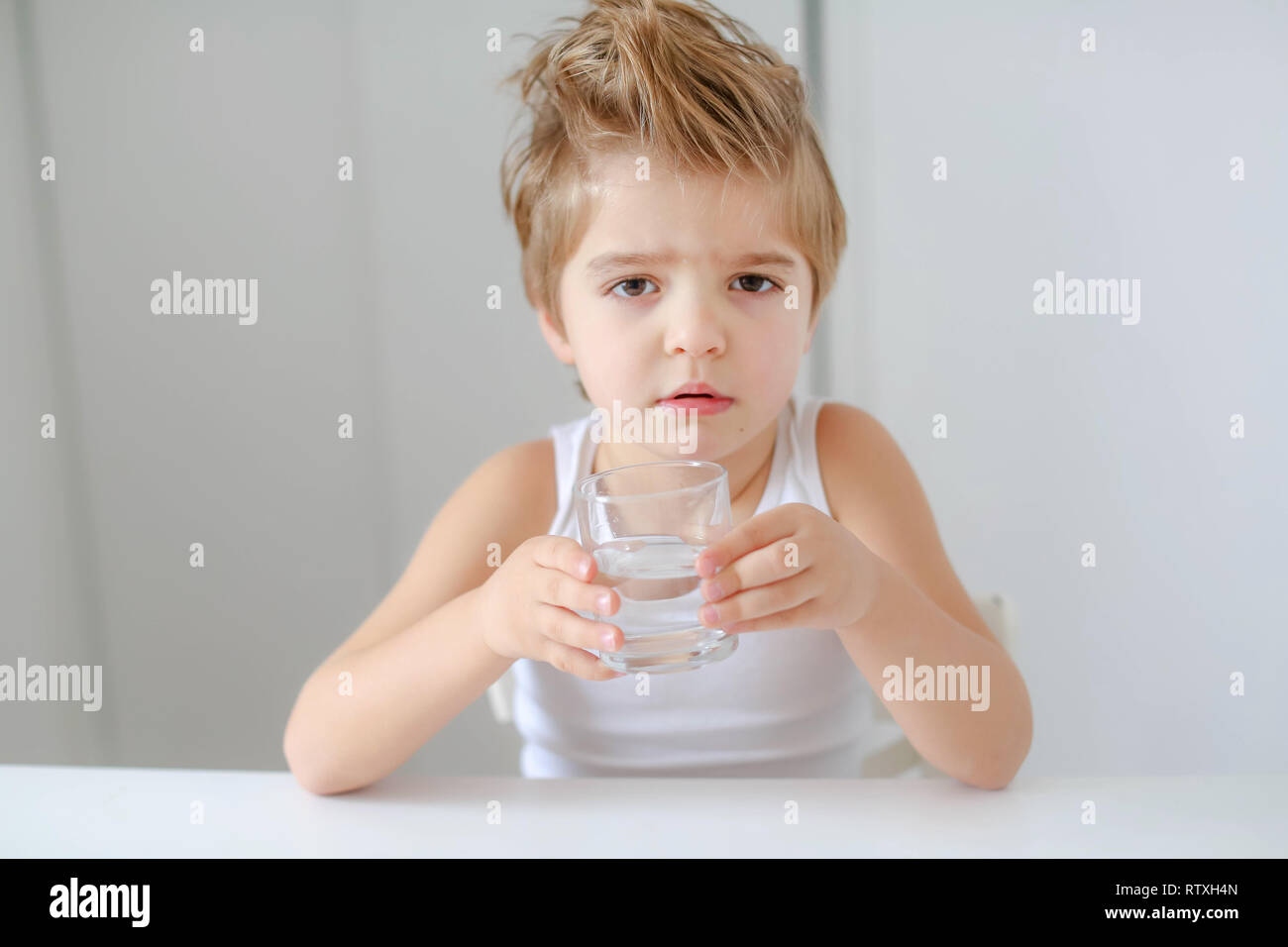 Cute smiling boy with glass of water isolated on a white background ...