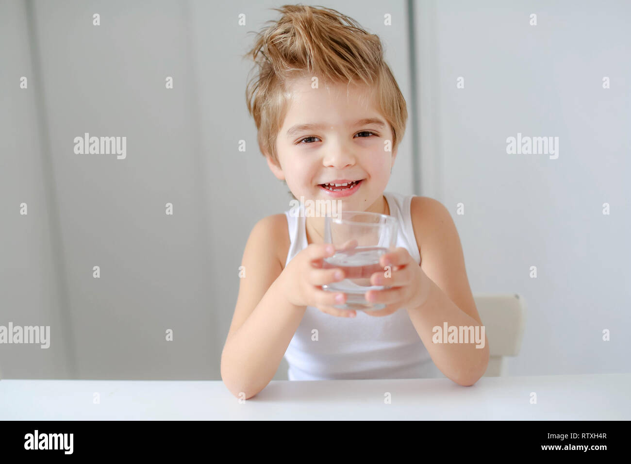 Cute smiling boy with glass of water isolated on a white background ...