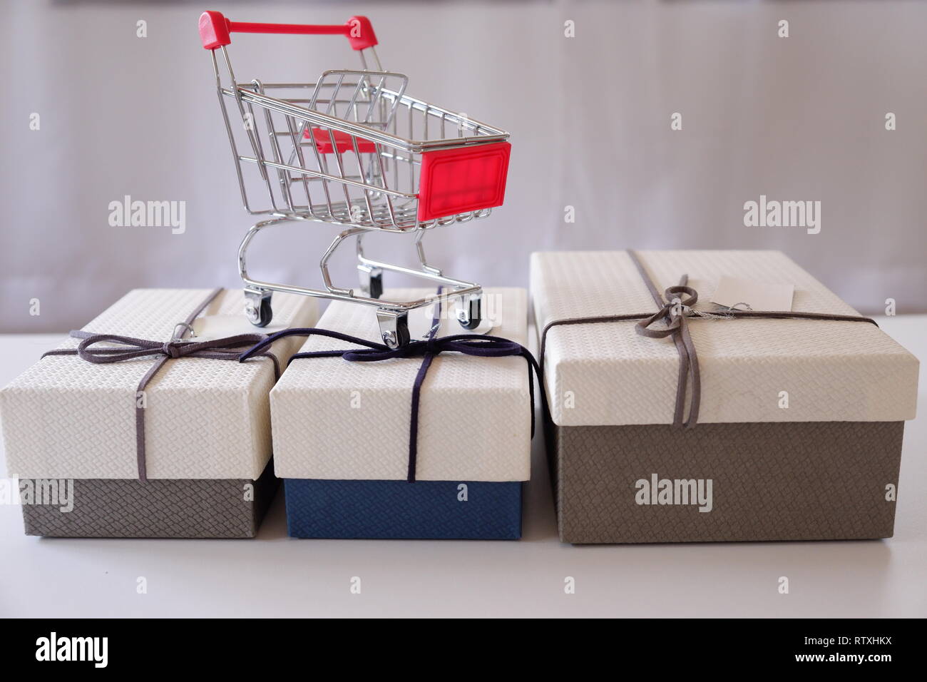 Close-up of gift boxes and shopping cart on white desk Stock Photo - Alamy